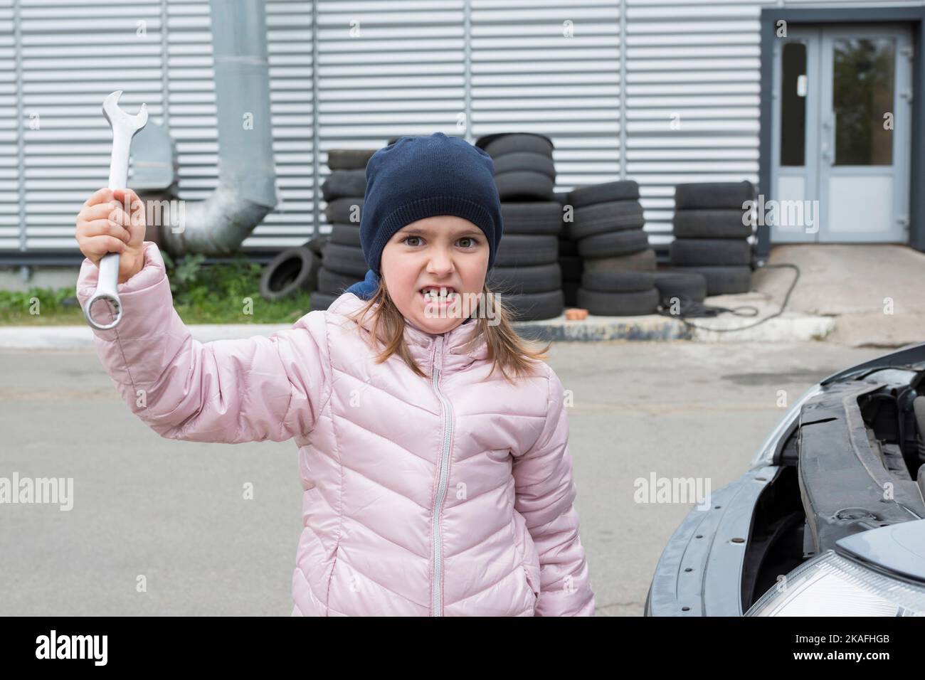 Child mechanic with a wrench on the background of the garage. Close-up ...