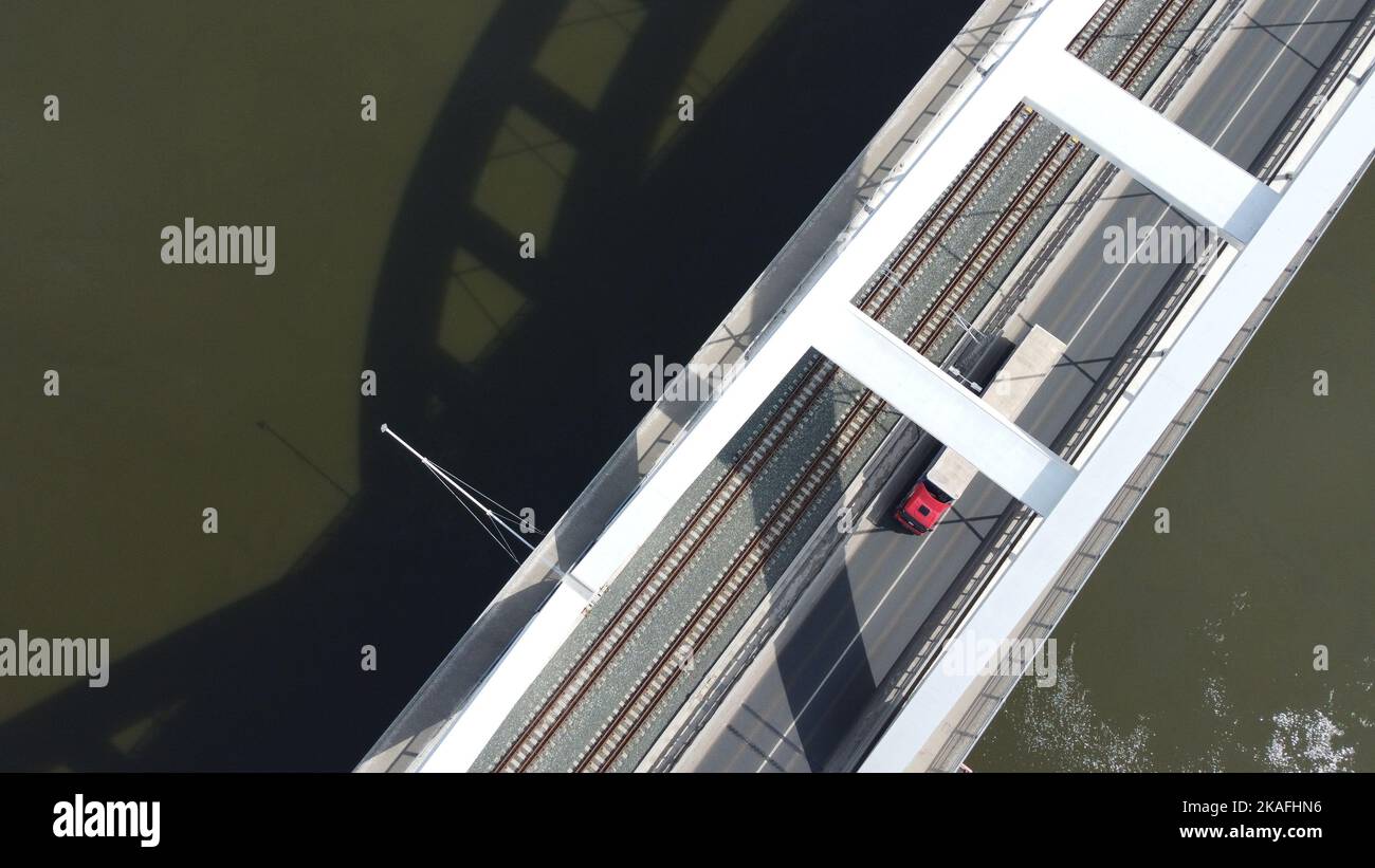The cargo bus crossing the urban bridge over green river, top view ...