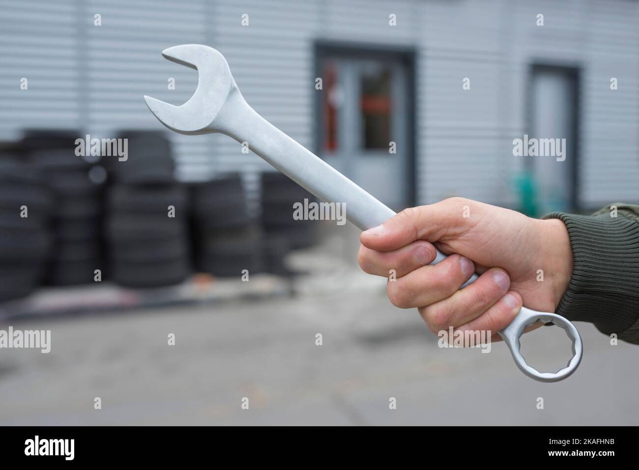Hand auto mechanic and wrench on the background of the garage. Auto ...