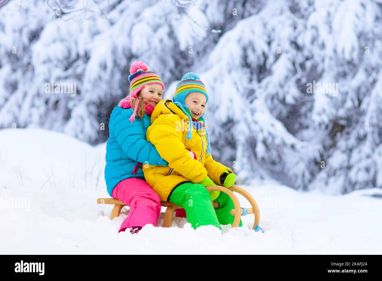 Little girl and boy enjoying sleigh ride. Child sledding. Toddler kid riding a sledge. Children ...