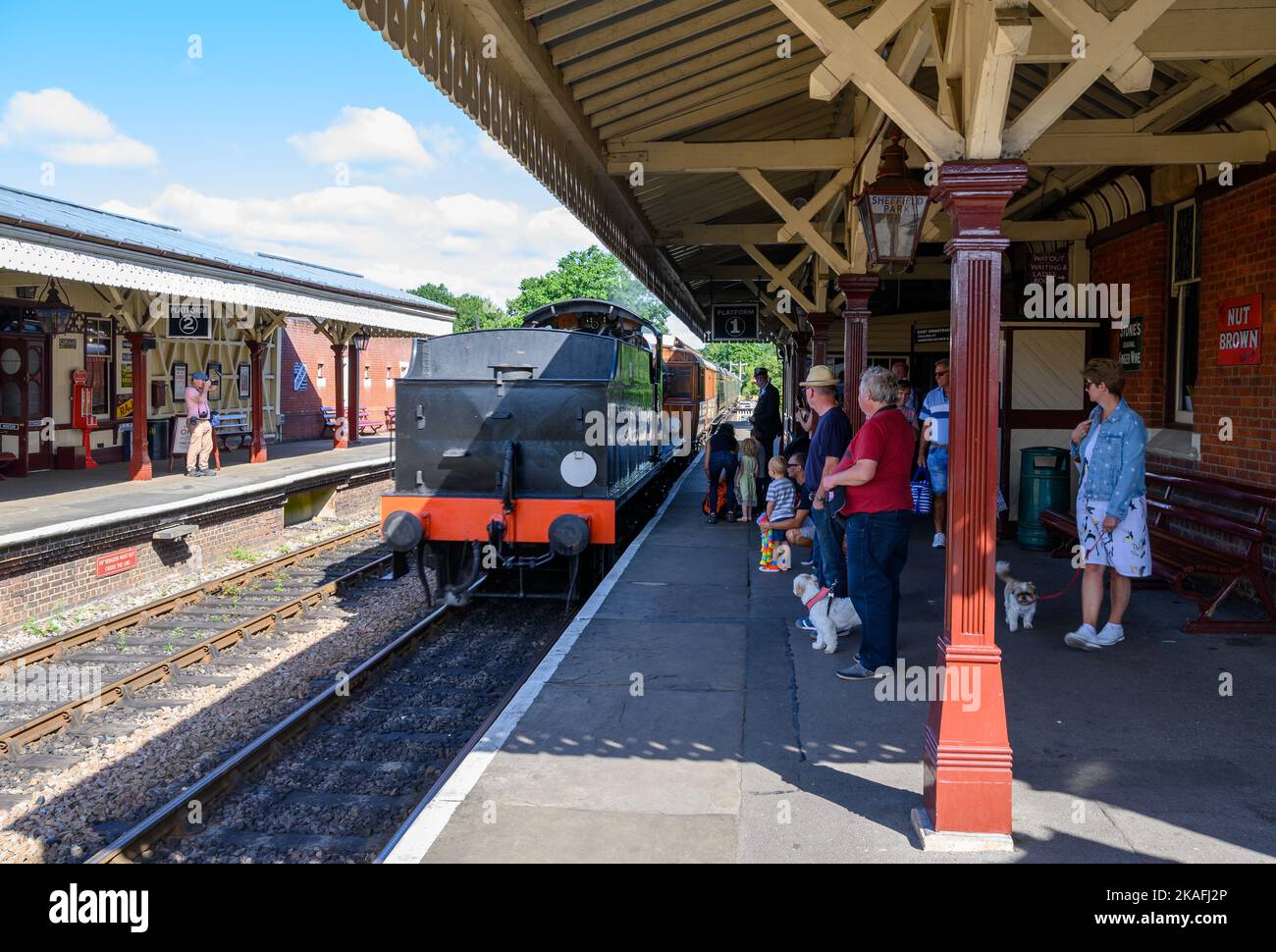 A vintage steam train approaching waiting passengers on platform 1 at ...