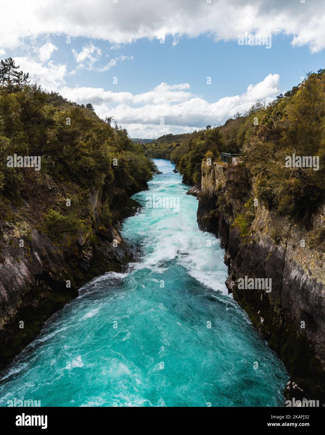 An aerial view of foamy Huka Falls waterfall flowing through cliffs on ...