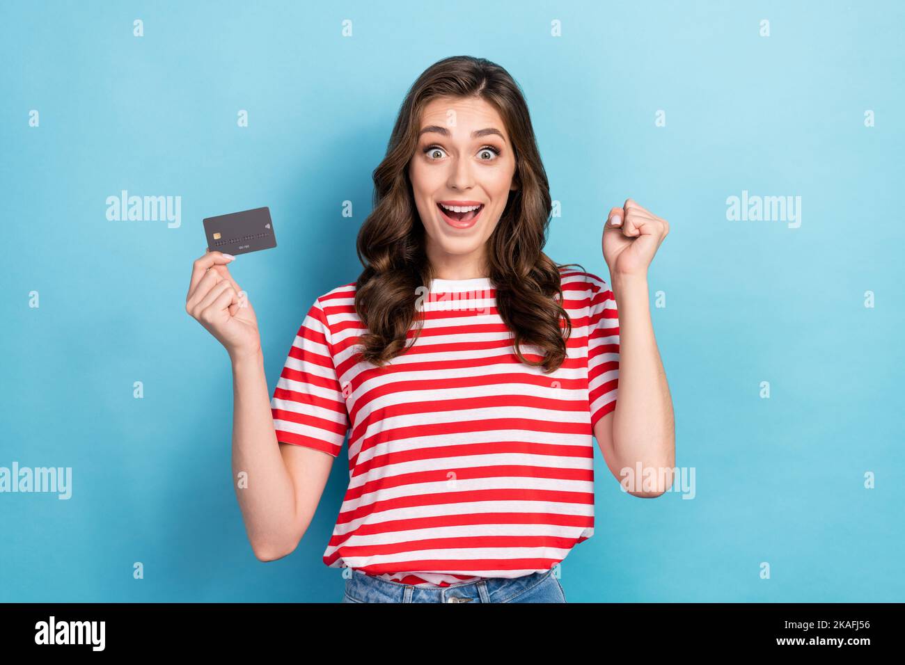 Photo of pretty lucky lady wear striped t-shirt rising bank card fist ...