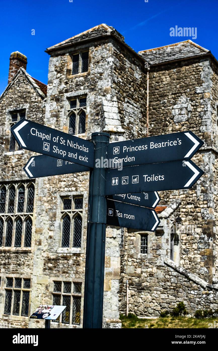 A vertical shot of street signs with a medieval building in the ...