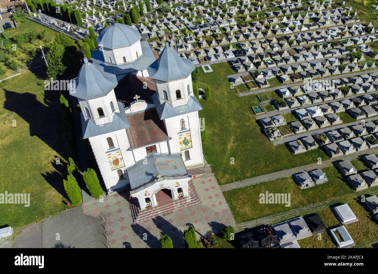 An aerial view of an orthodox church and a cemetery located in Reghin ...