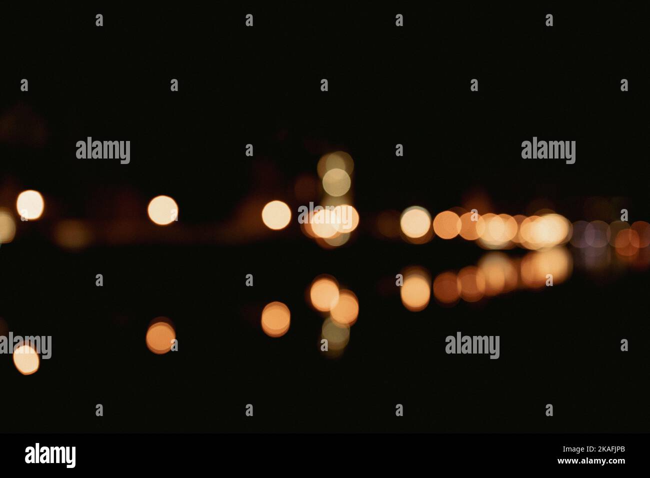 Defocused street lamps and reflection on a water, night city life ...