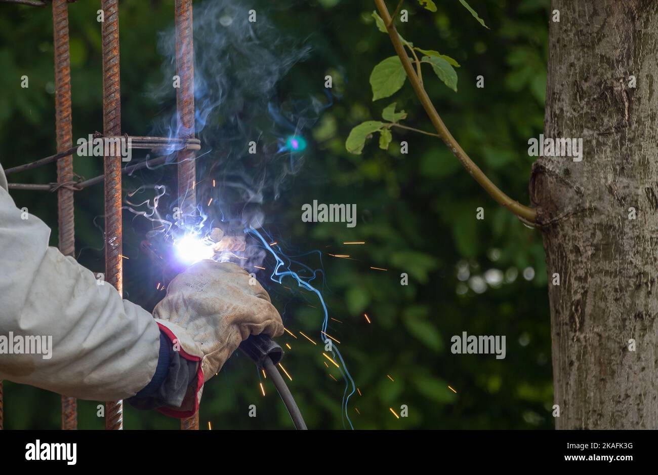 A worker welds rebar in nature, construction start concept - Green ...