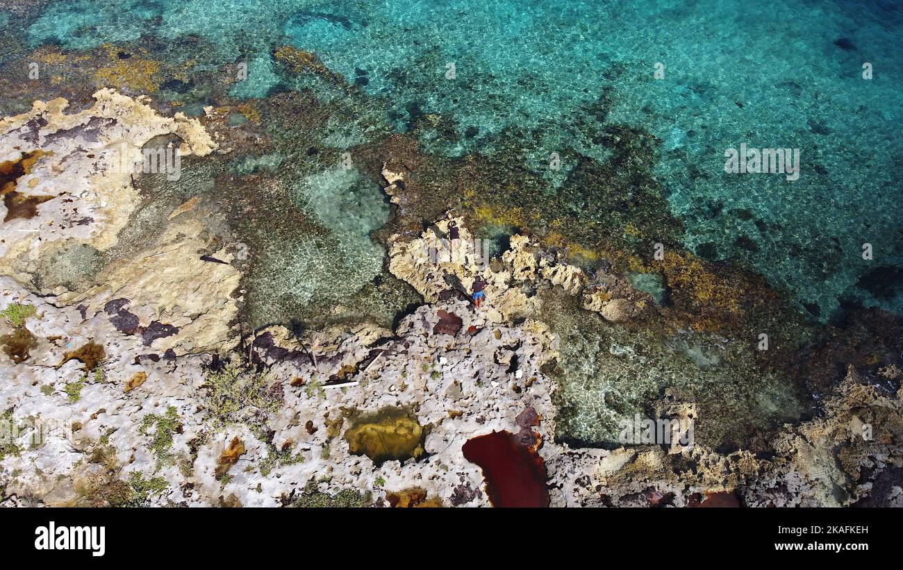An aerial shot of a turquoise sea meeting the rocky shore during ...