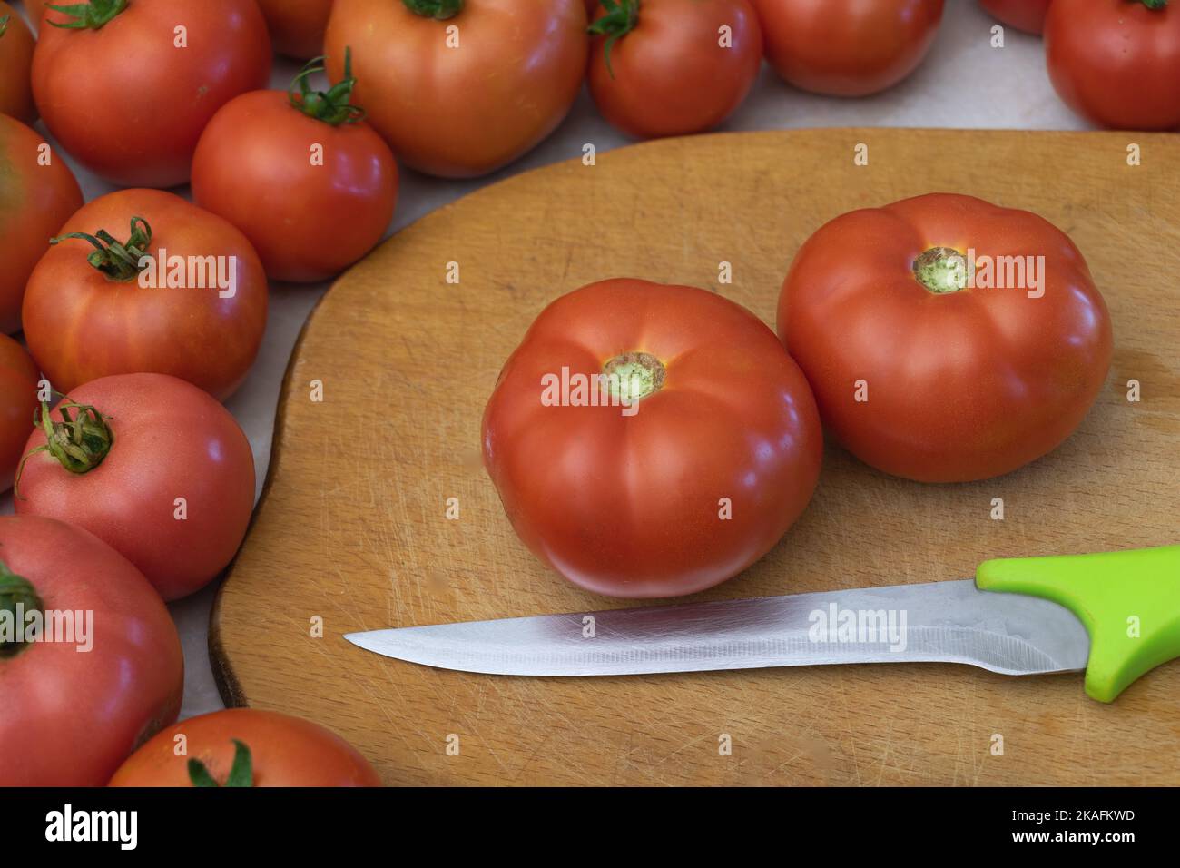 A few fresh homemade tomatoes and a knife on a wooden chopping board ...
