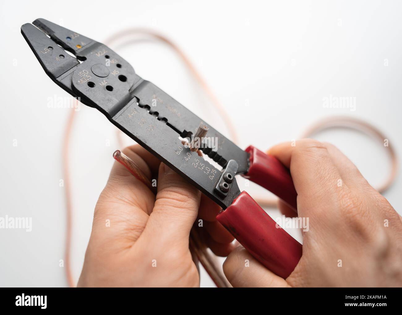 A closeup of hands using a Crimping Pliers to cut a wire on white ...
