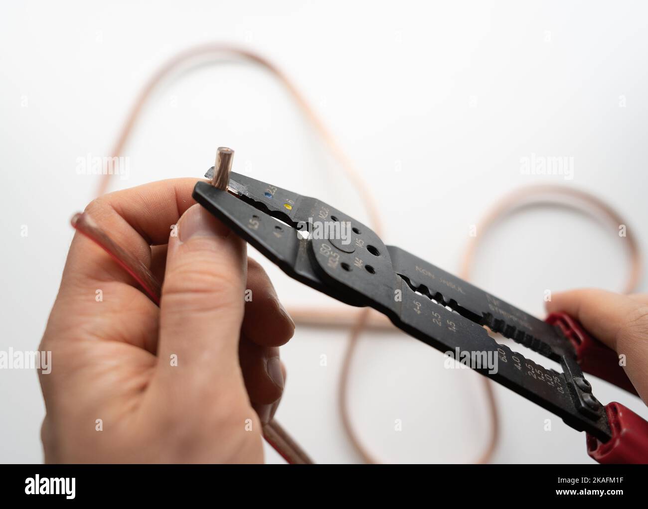 A closeup of hands using a Crimping Pliers to cut a wire on white ...