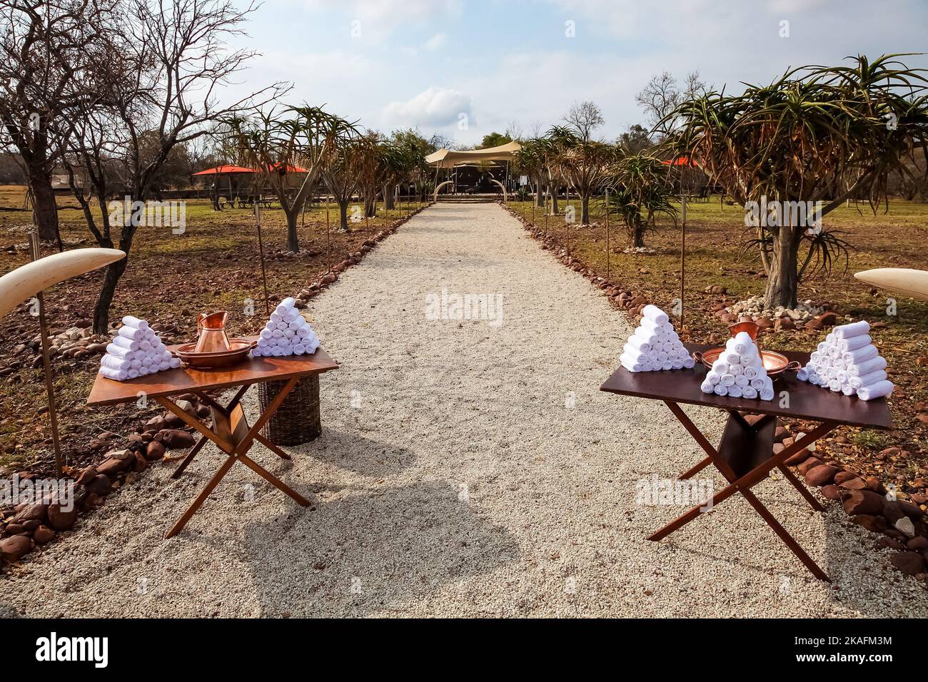 A resort entrance with a sandy path and tables full of white towels ...