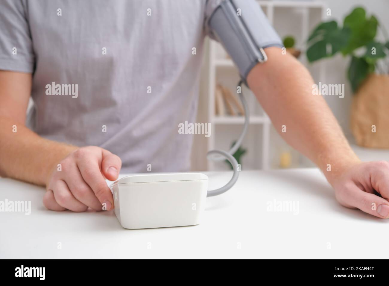 A man measures blood pressure with a white electric tonometer lying on ...