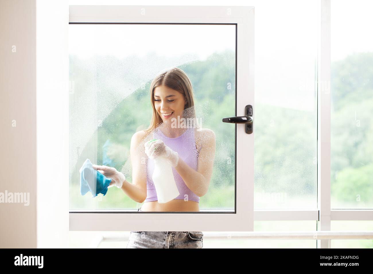 Young woman washing window with sponge in office Stock Photo - Alamy