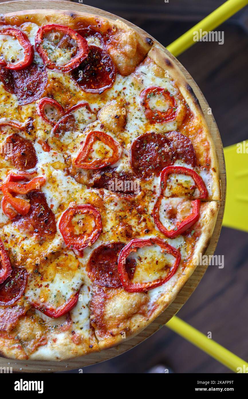 A freshly baked pizza on the board with tomato, pepperoni and cheese ...