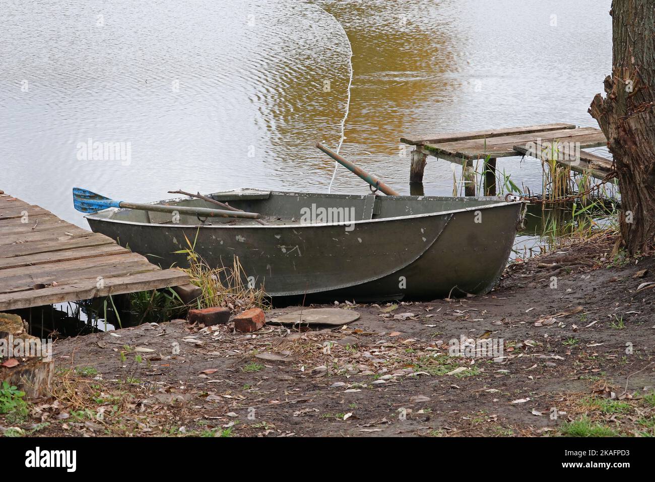 A metal boat with oars on the shore of the lake. Fisherman's boat Stock ...