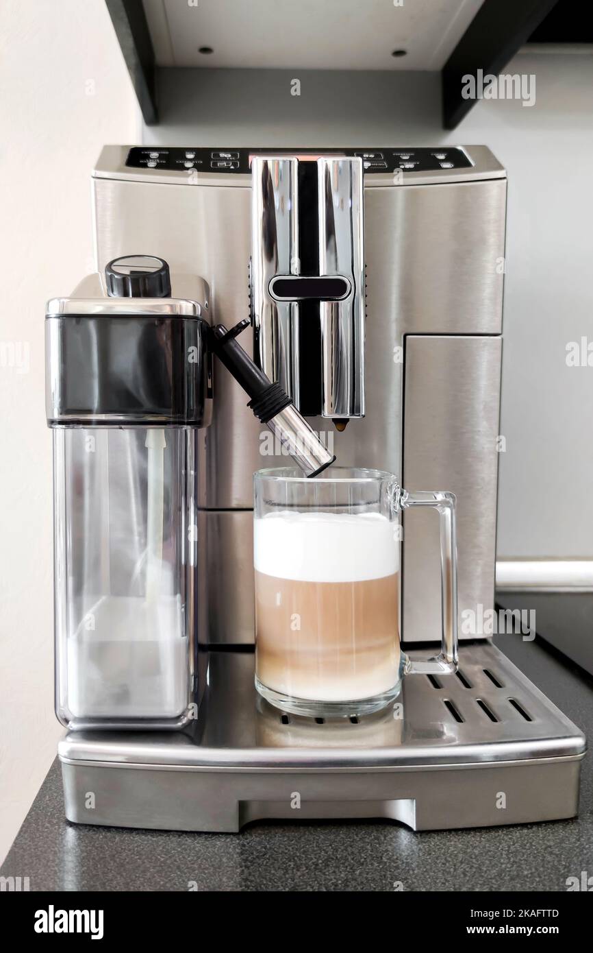 Cappuccino coffee in glass cup stands on stand of coffee machine, close ...