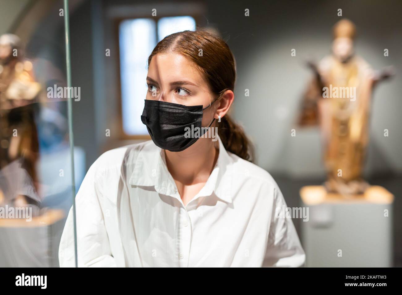 Woman in mask visiting exhibit at sculpture hall in museum Stock Photo ...