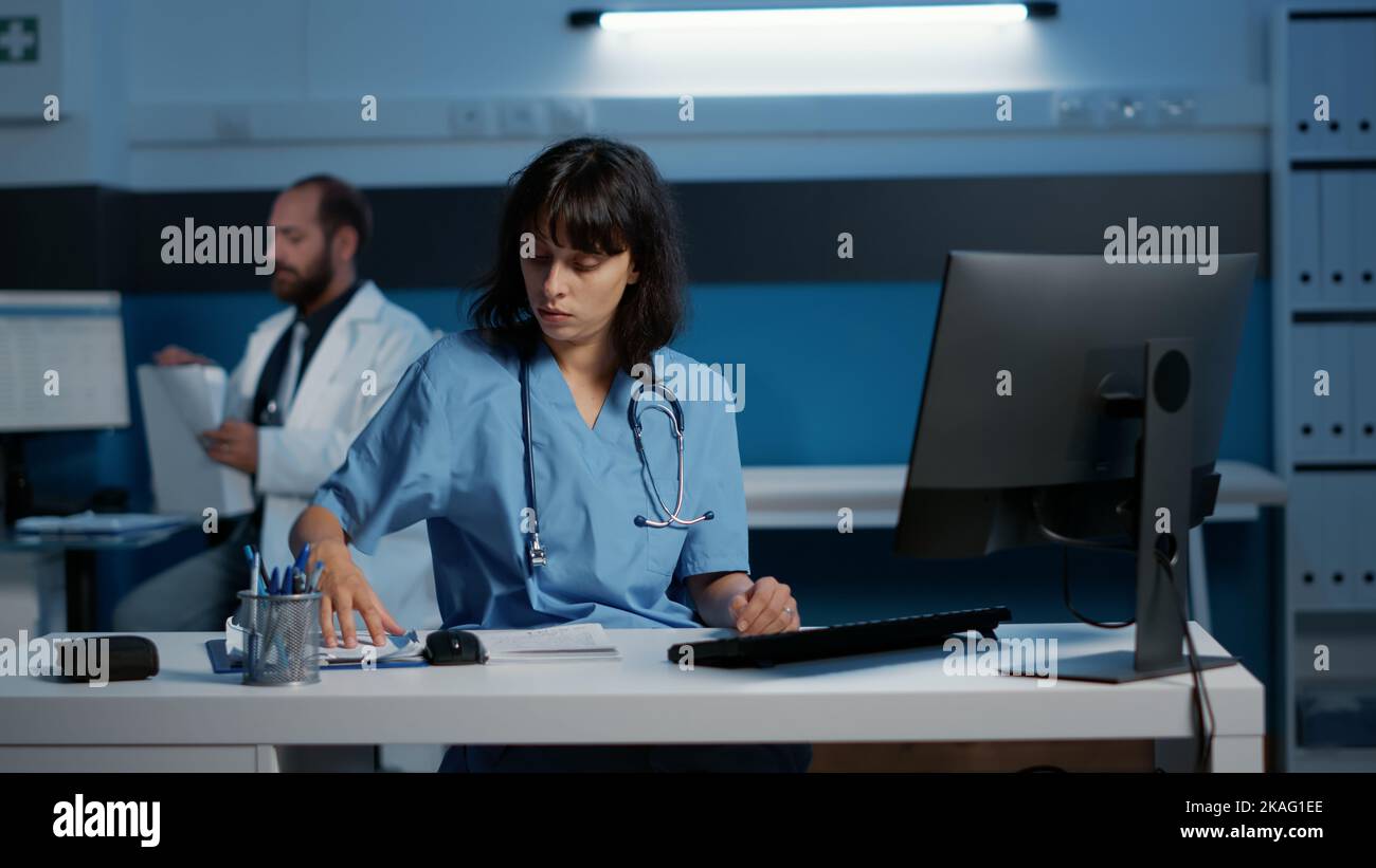 Medical assistant standing at desk analyzing patient medical report ...