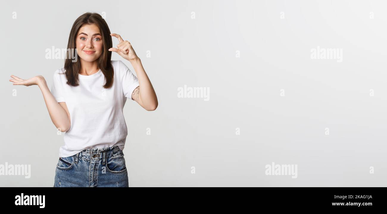 Skeptical and unamused brunette girl showing something too small, tiny ...