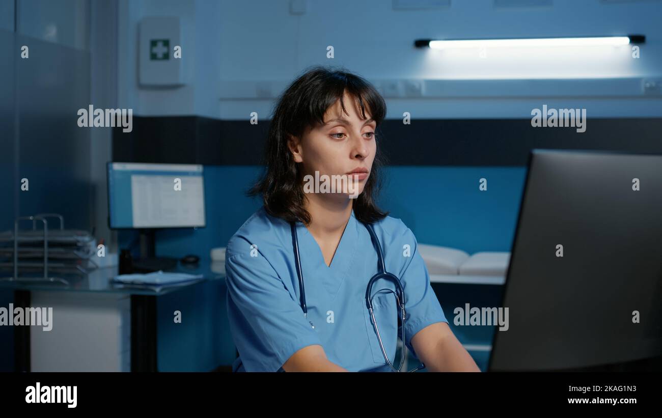 Tired assistant working over hours in hospital office analyzing patient ...