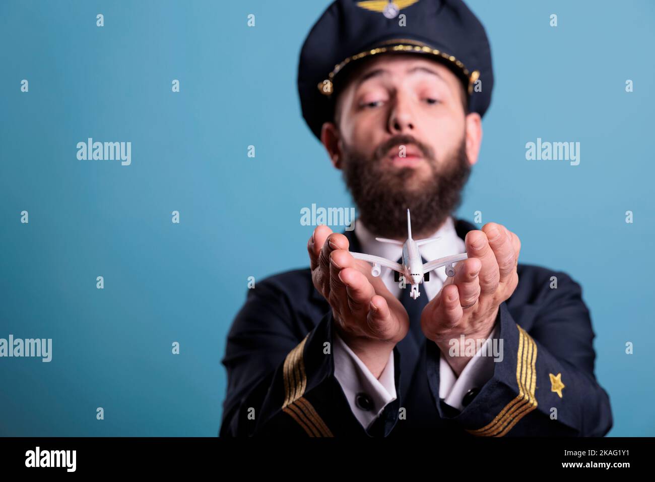 Airplane captain in uniform holding plane model in palms front view ...