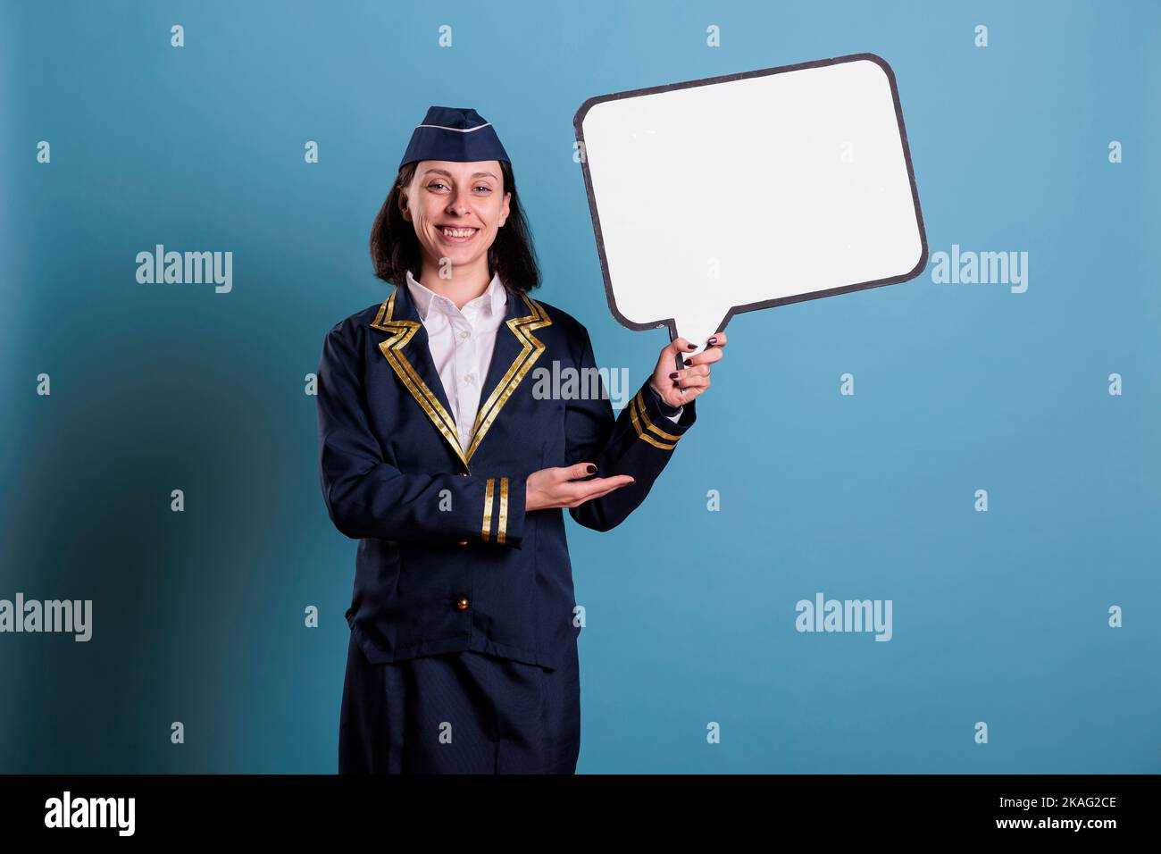 Portrait of stewardess holding white blank speech bubble, showing thumb ...
