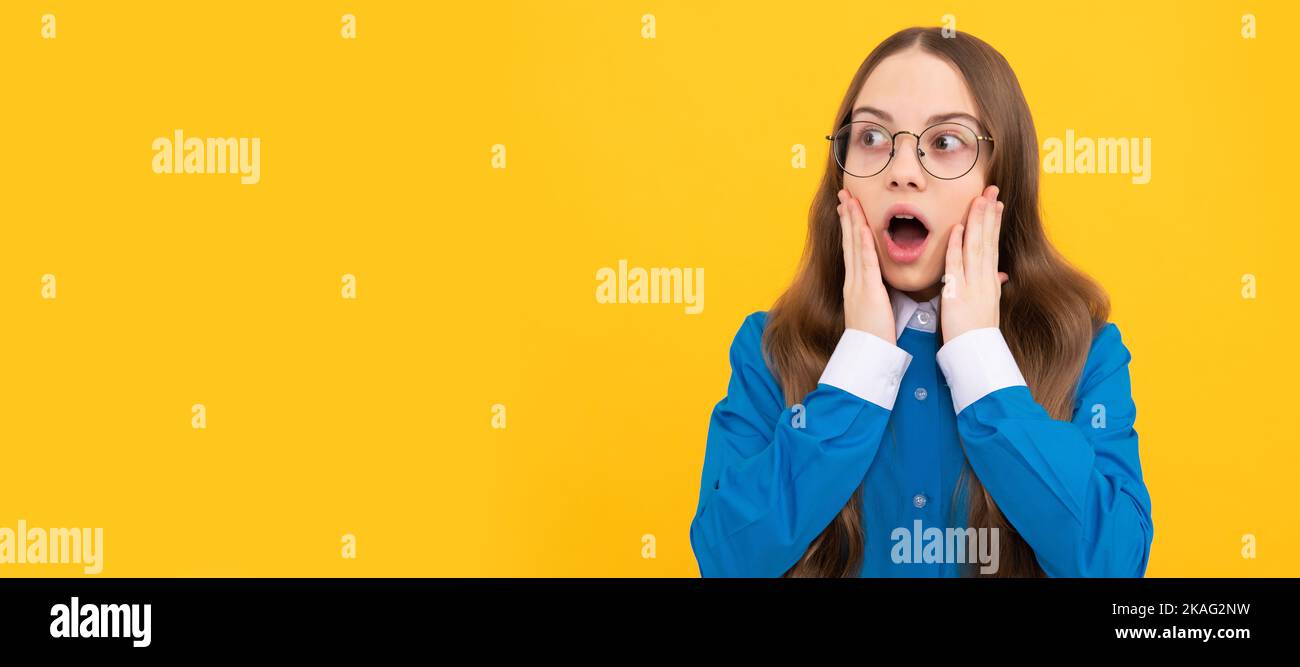 Shocked girl child in eyeglasses school education yellow background ...