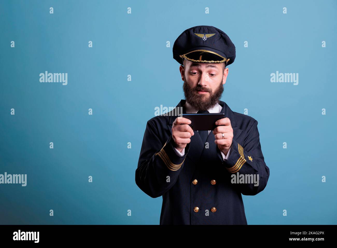 Plane pilot in professional uniform playing mobile games on smartphone ...