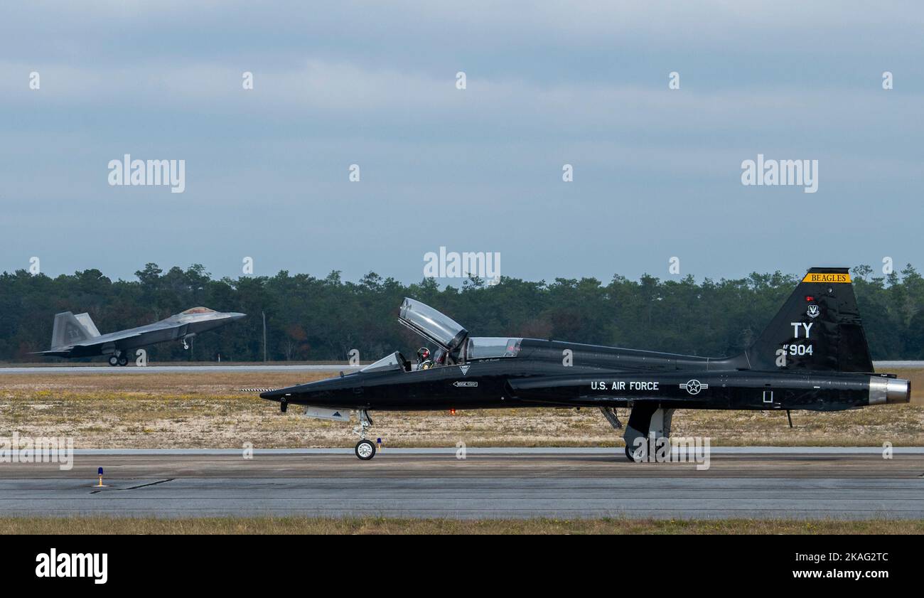 A 325th Fighter Wing T-38 Talon taxies as an F-22A Raptor takes off for ...