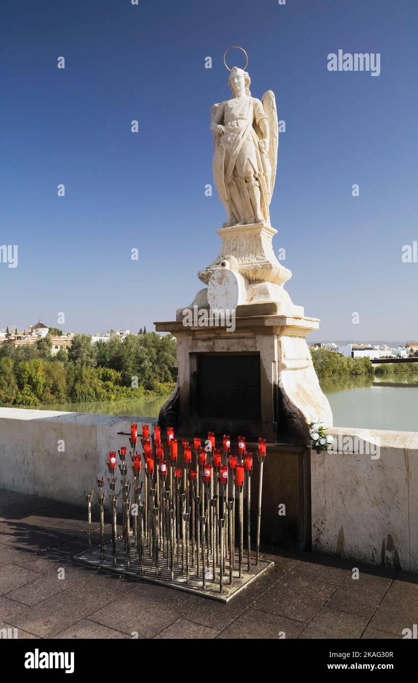 Statue and votive candles on the Roman bridge that spans the ...