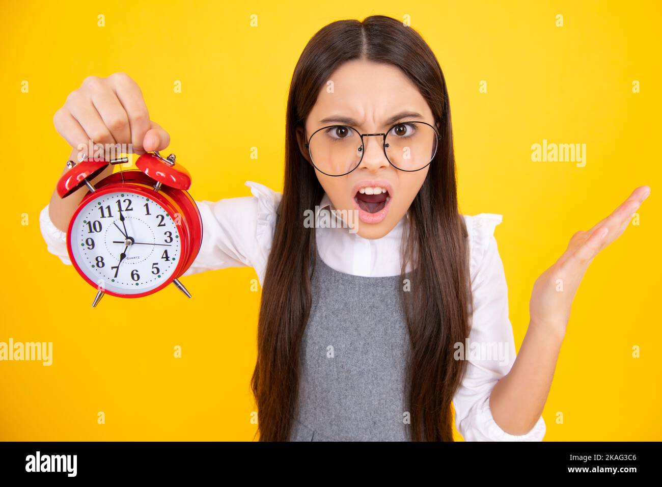 Teen student girl with clock isolated on yellow background. Child back ...