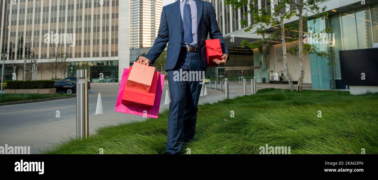 cropped businessman in suit hold packages and gift box walk outside the ...