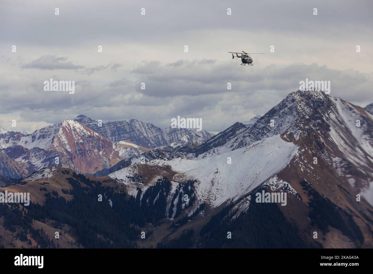 An LUH-72 Lakota helicopter is flown above mountainous terrain near ...