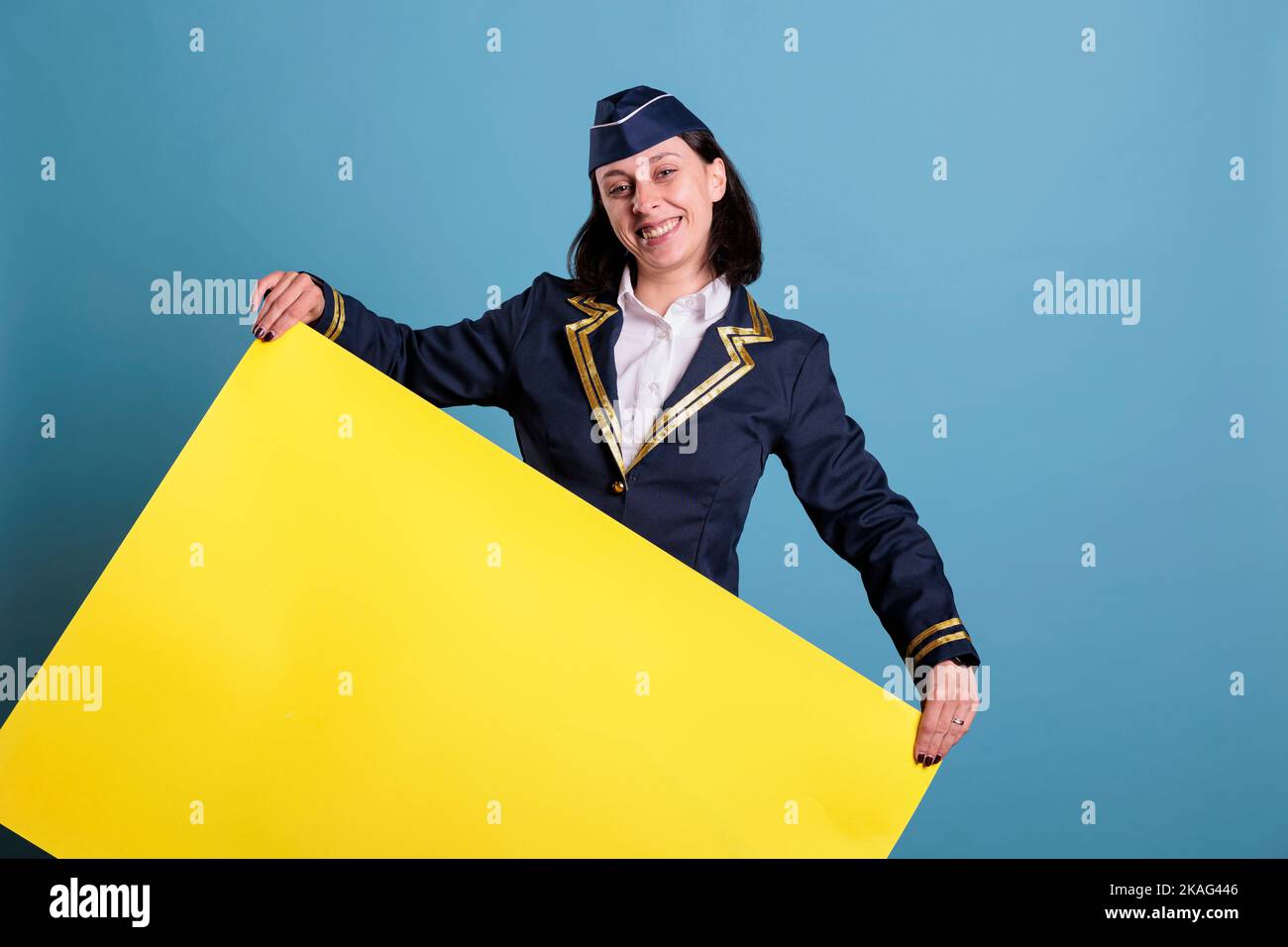 Smiling stewardess holding yellow empty advertising banner with copy ...