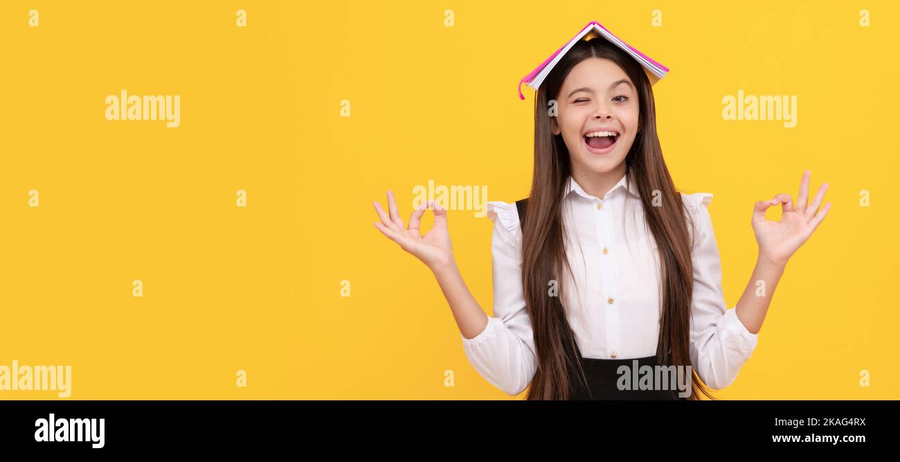 Absorbing the knowledge. Happy school girl hold book on head making ...