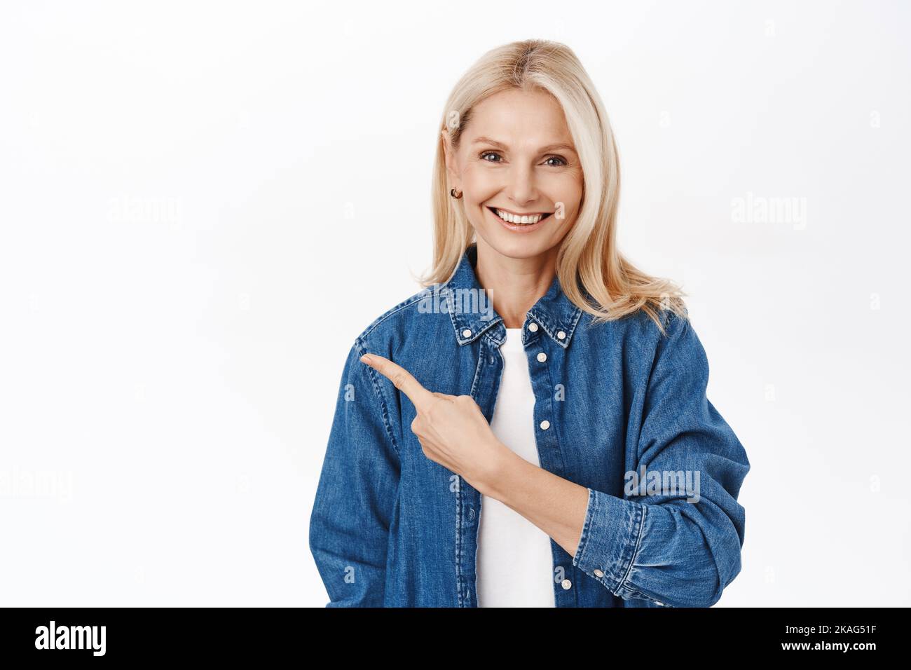 Portrait of smiling blond senior woman, stylish grandmother pointing ...