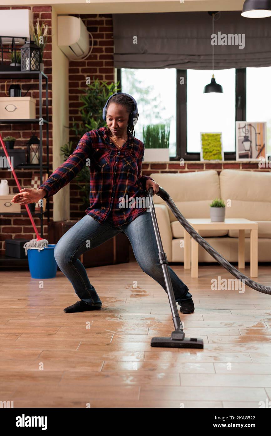 Positive housewife enjoying spring cleaning at home, singing while ...