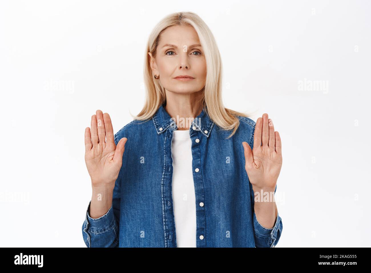 Stop it. Serious blond senior woman, showing stop sign, prohibit, makes ...