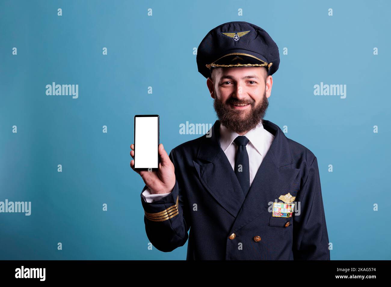 Smiling airplane pilot showing smartphone with blank white screen ...