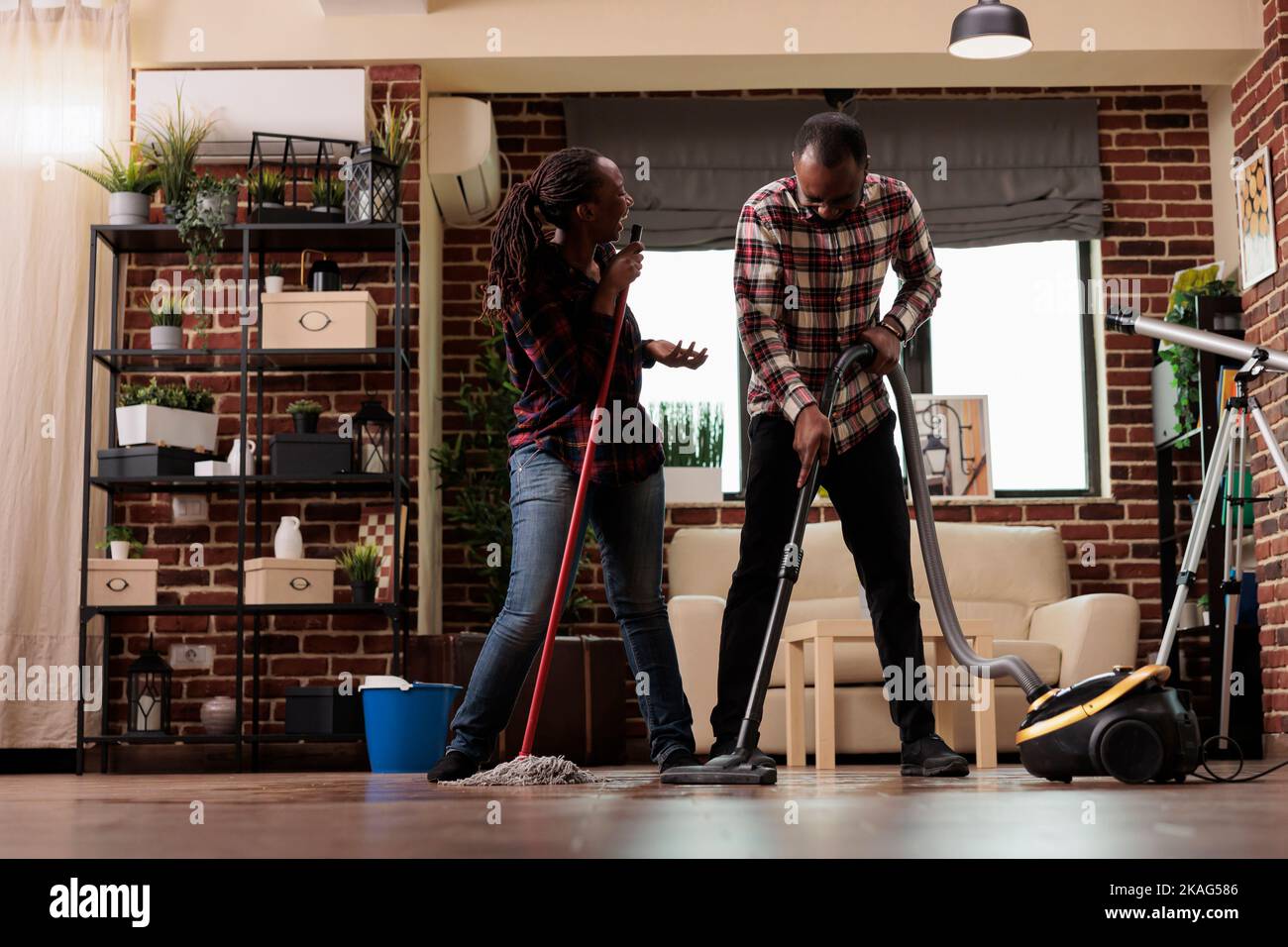 African american couple having fun at home cleaning, singing laughing ...