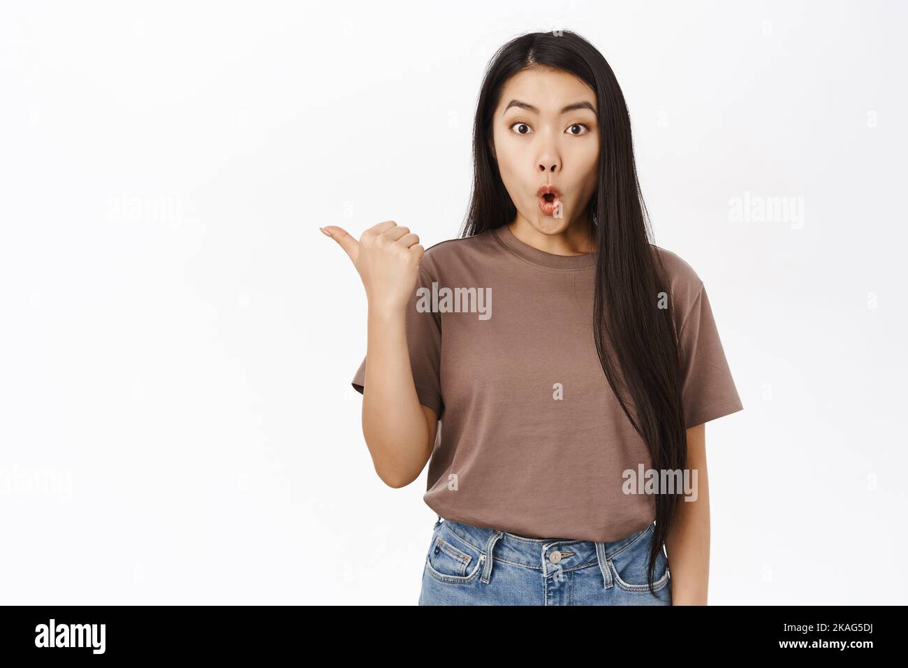 Portrait of amazed asian girl points at banner, shows loog with ...