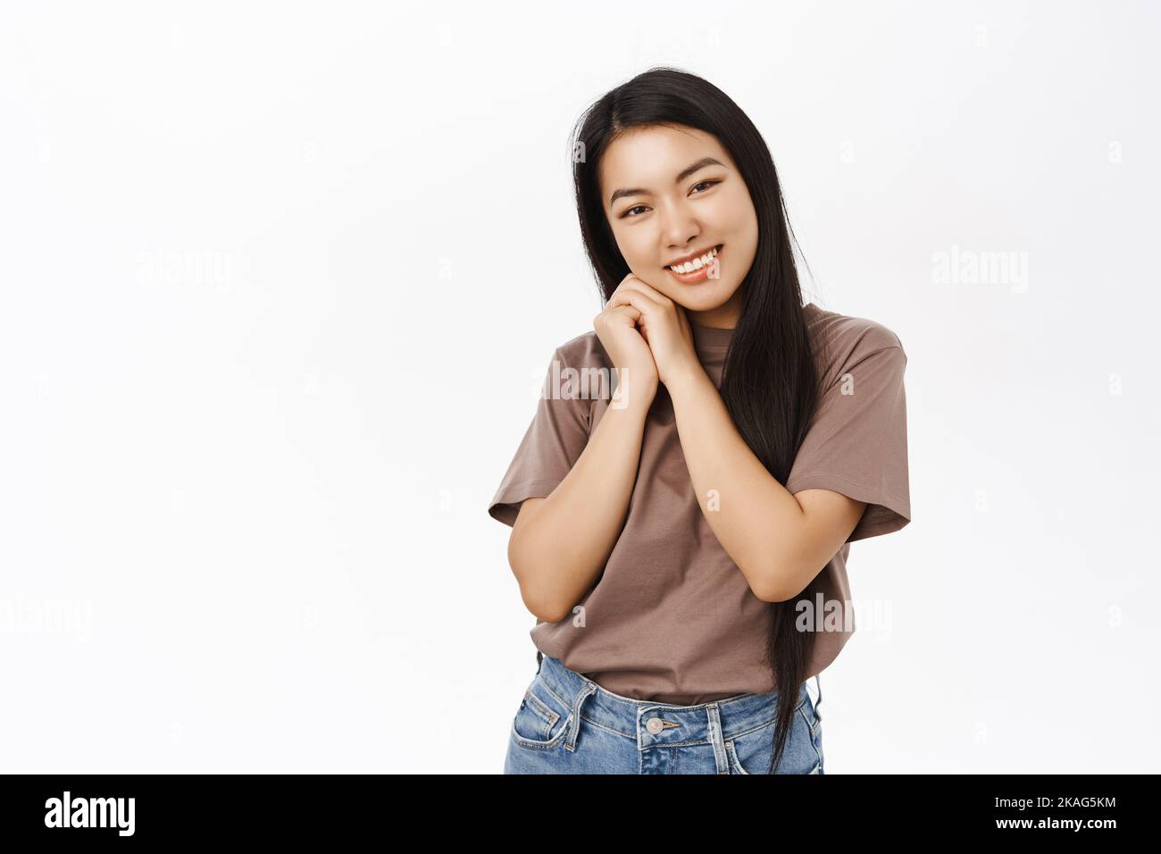 Beautiful korean girl looking with flattered, delighted face, pleased by smth, gazing at smth ...