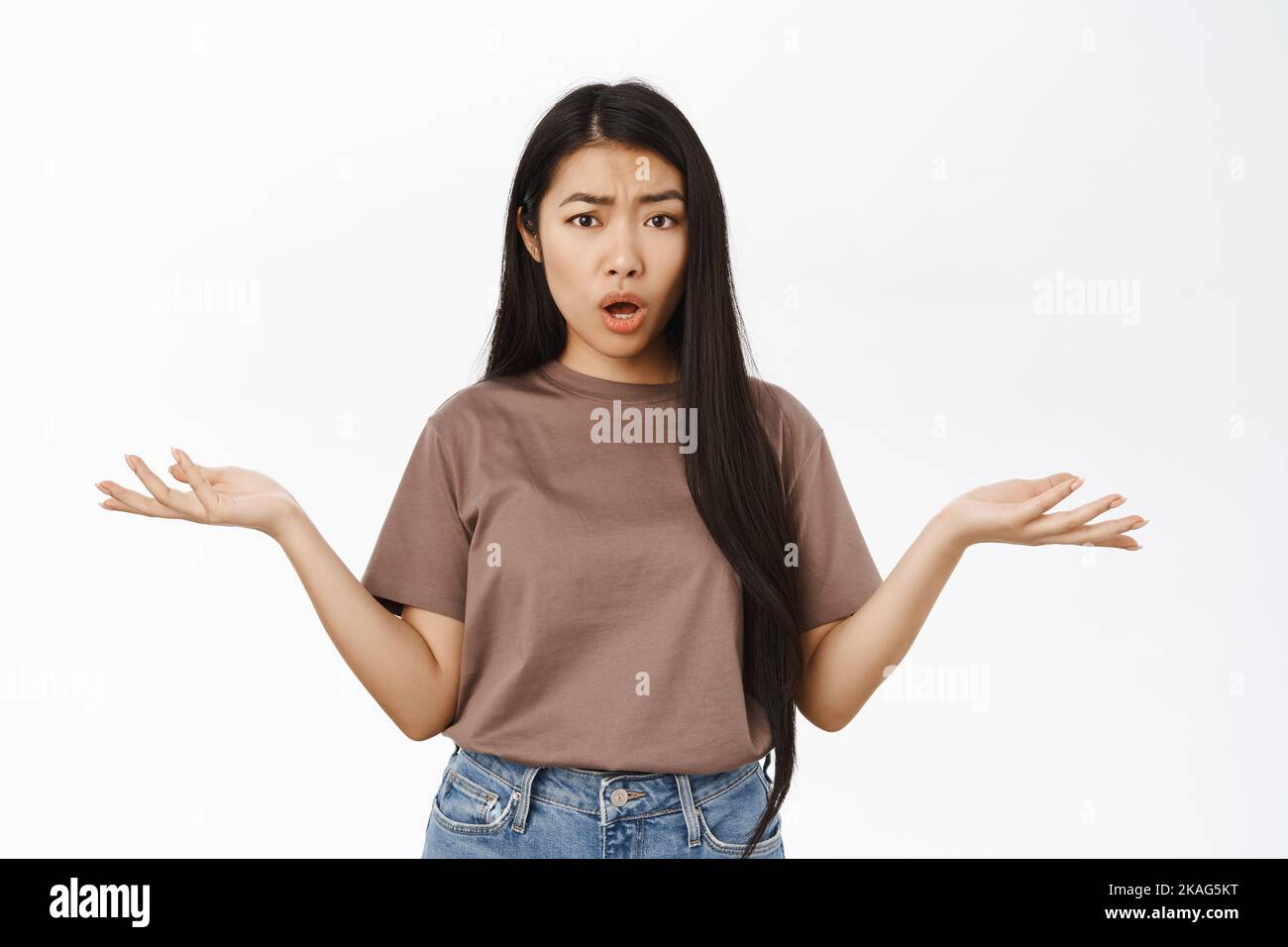 Confused asian girl shrugs, looks puzzled and worried, stands over ...