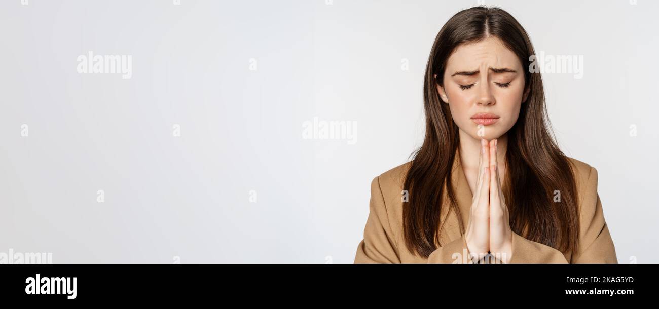 Sad hopeful businesswoman praying, close eyes and supplicating, close ...