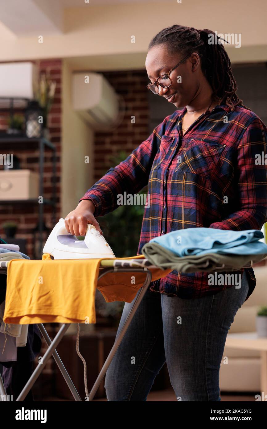 Independent african american woman using steam iron at home, takes ...