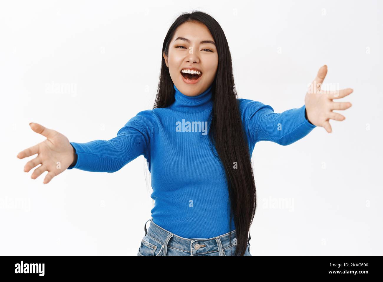 Smiling asian girl extends hands, friendly hug, inviting for cuddle ...
