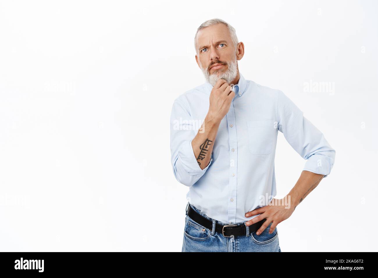 Portrait of businessman thinking, touching beard and looking skeptical ...