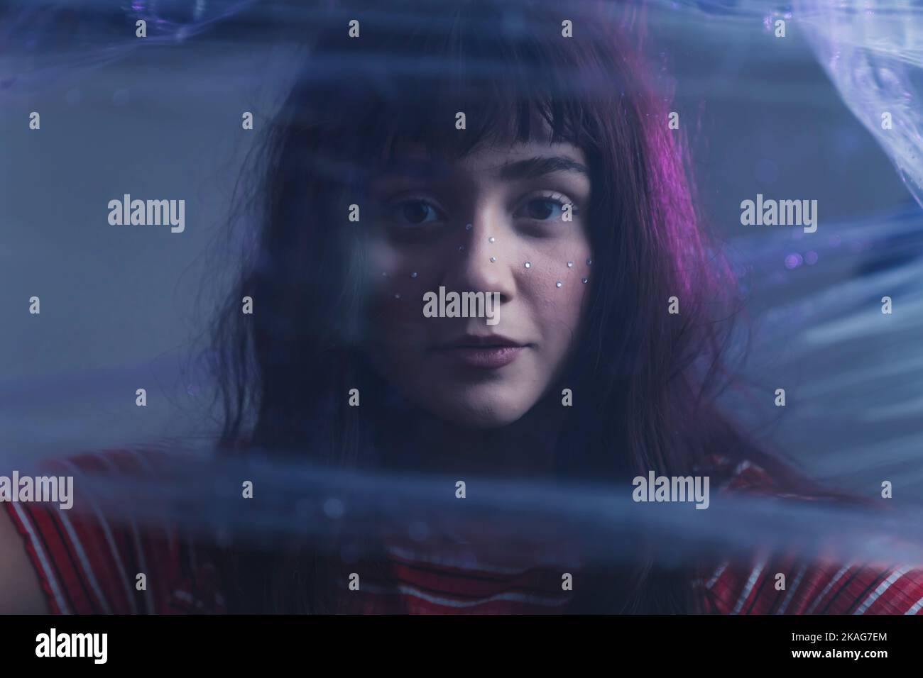 Caucasian young adult woman in creative makeup with purple hair looking ...