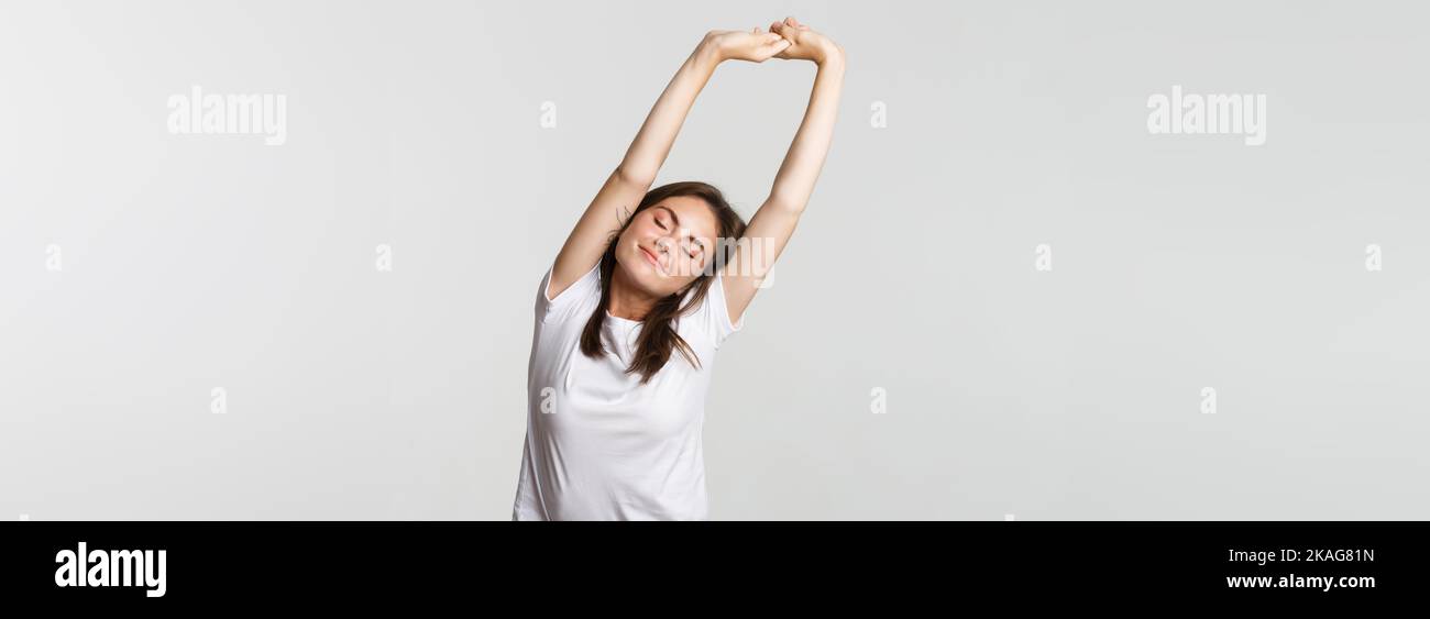 Portrait of relaxed carefree brunette girl stretching with satisfied ...